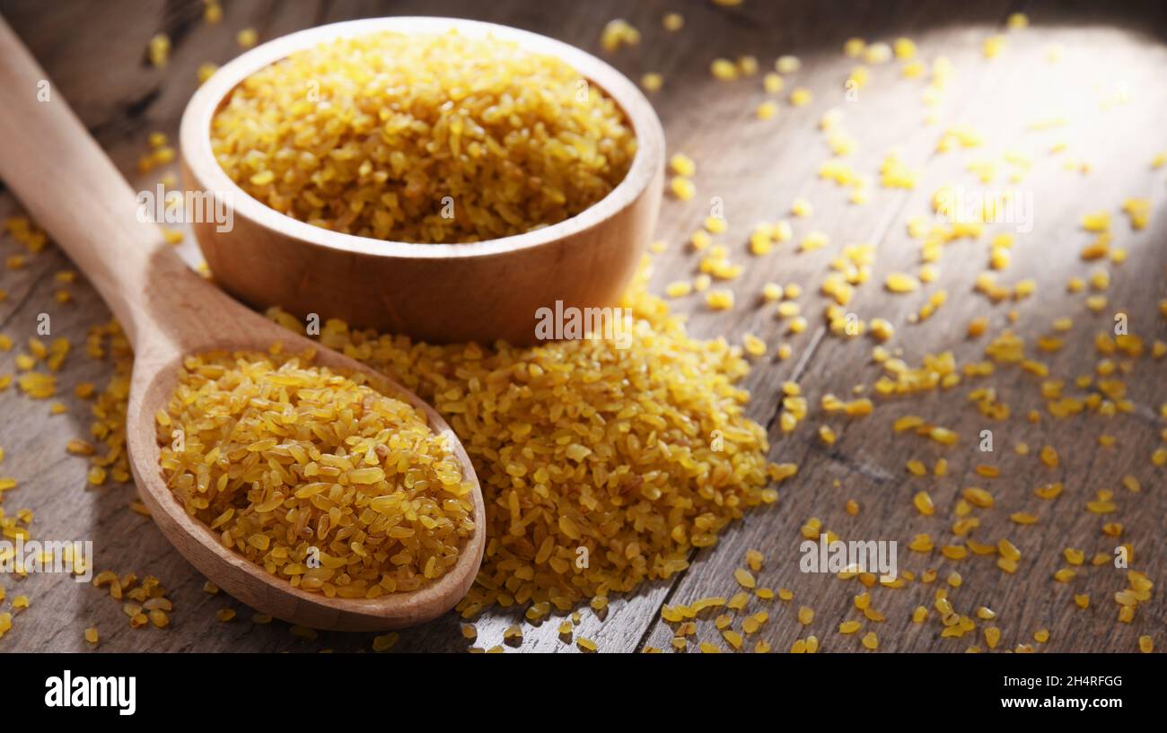 Composition with a bowl and spoon of uncooked bulgur on a table Stock ...