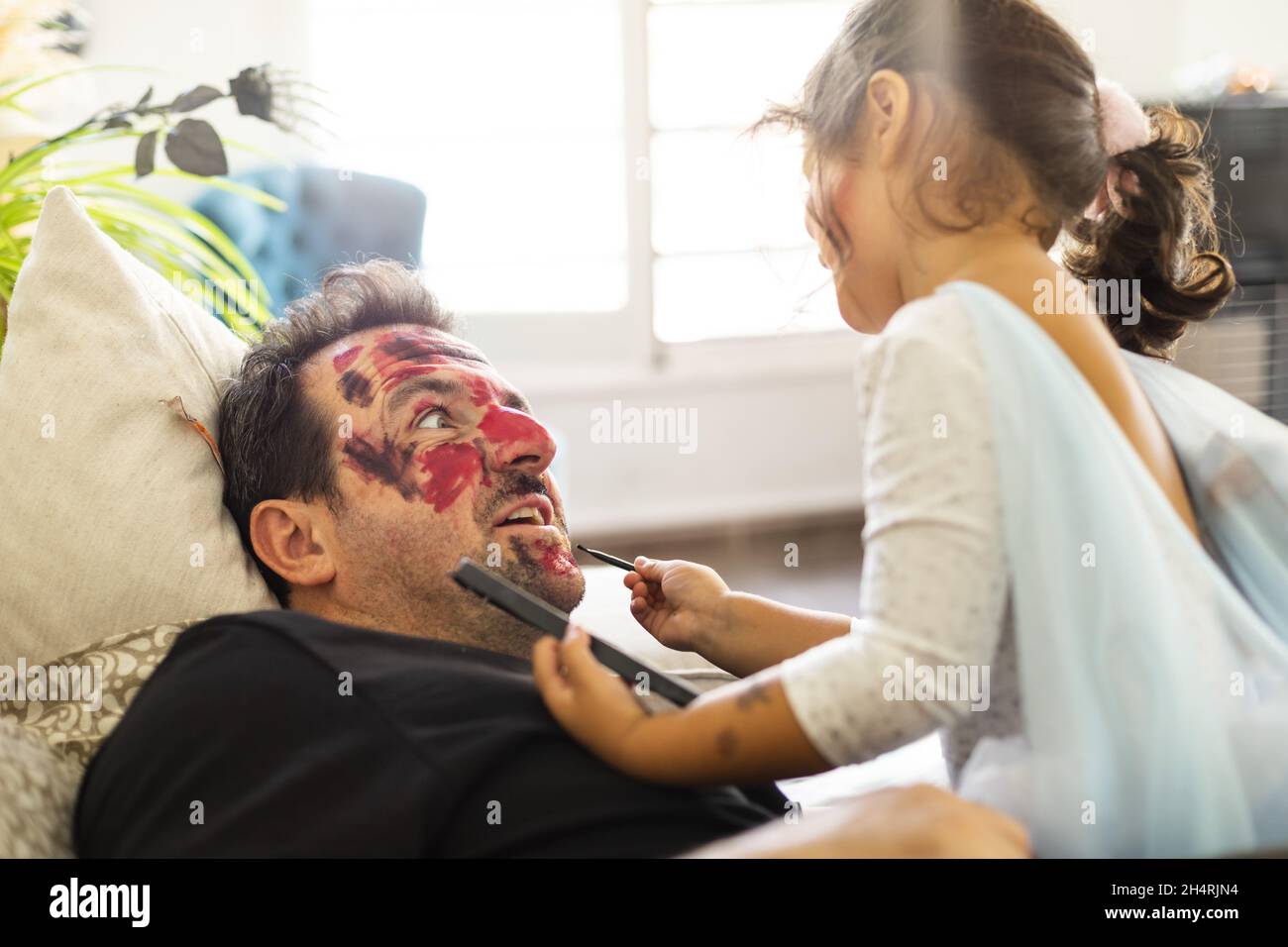 Little girl doing her father's Halloween makeup Stock Photo - Alamy