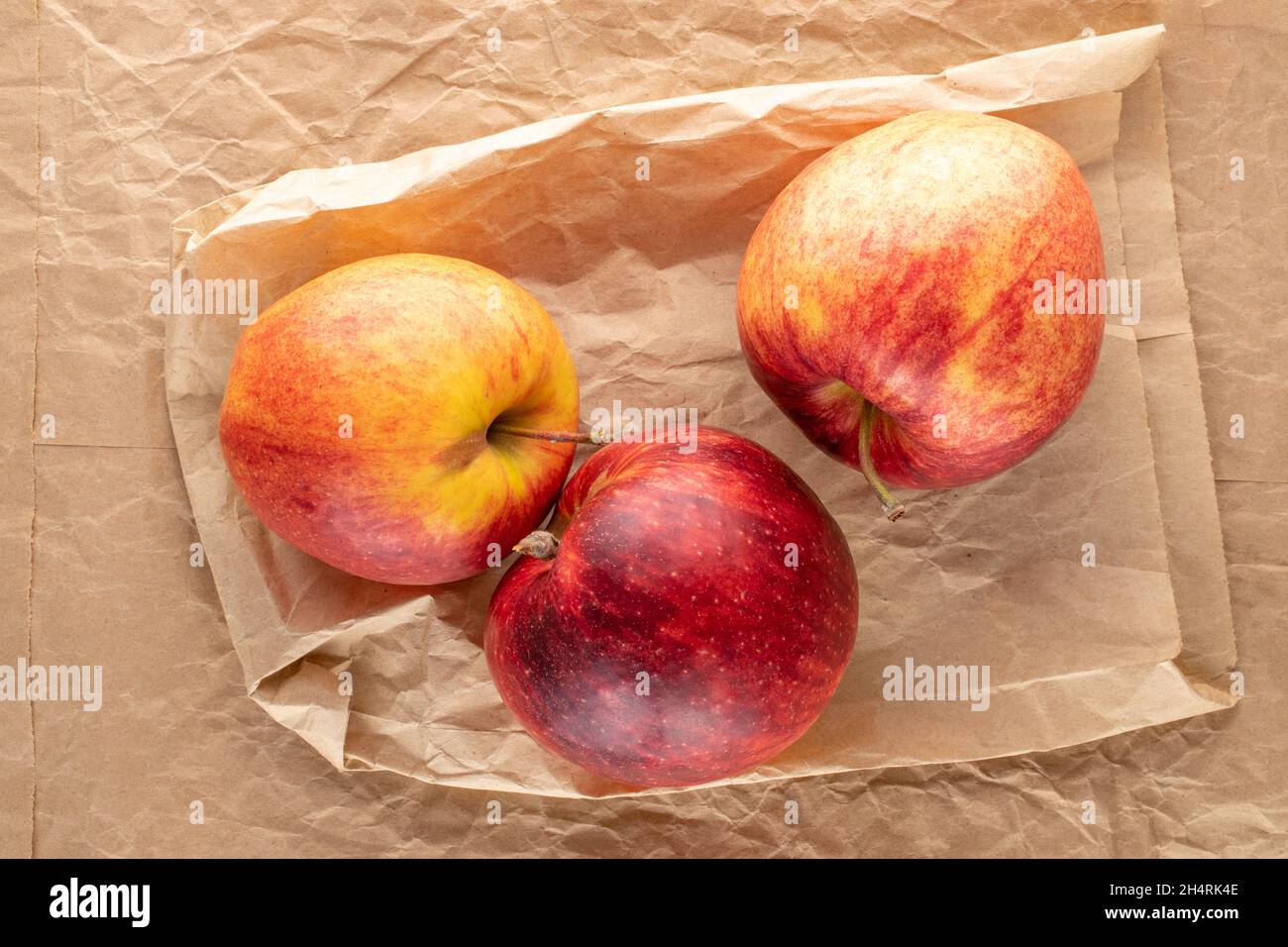 Three organic red apples on craft paper, close-up, top view Stock Photo ...