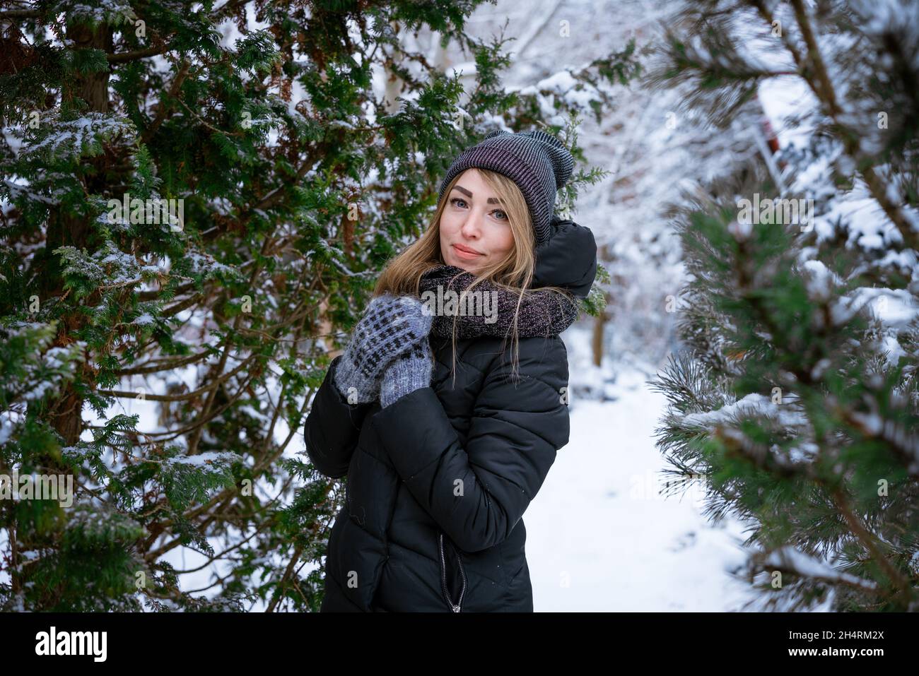 Beautiful woman standing among snow-covered trees in winter forest and ...