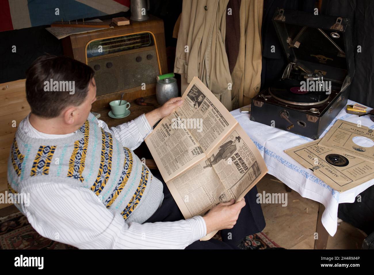 1940s Britain: Man smoking pipe, reading newspaper while listenning to ...