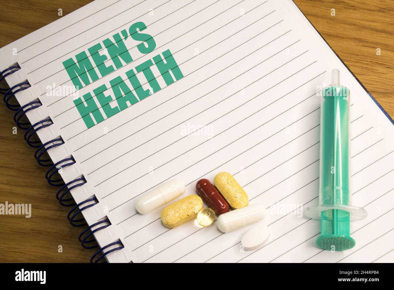 Different pills and a syringe needle on a notepad with a "men's health ...