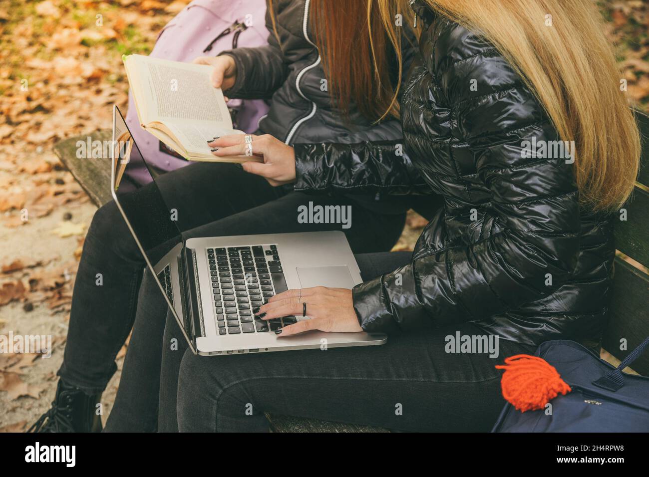 Girls study sitting on a bench in the park in a beautiful autumn ...