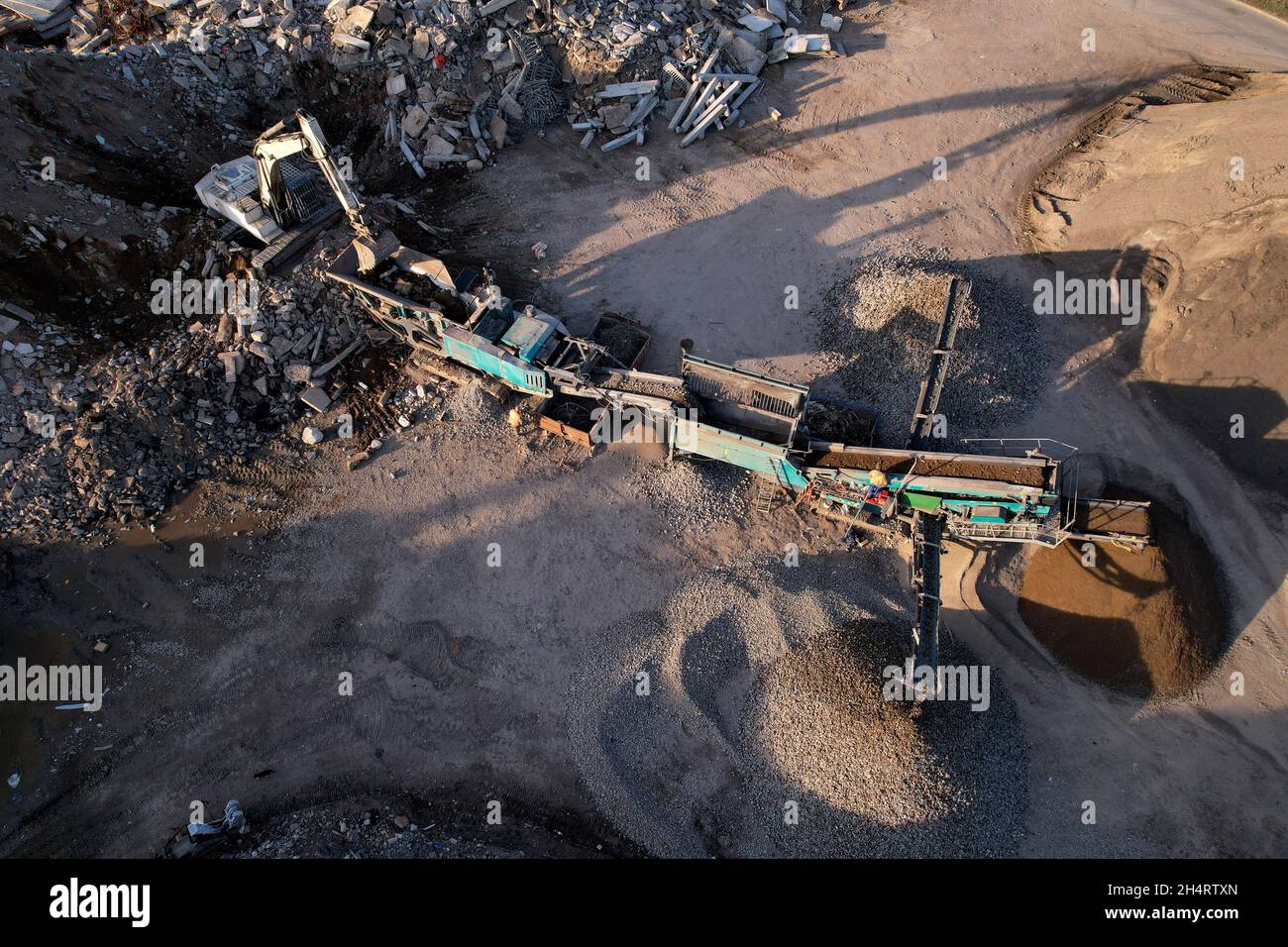 Excavator at landfill the load concrete waste in a mobile jaw crusher ...