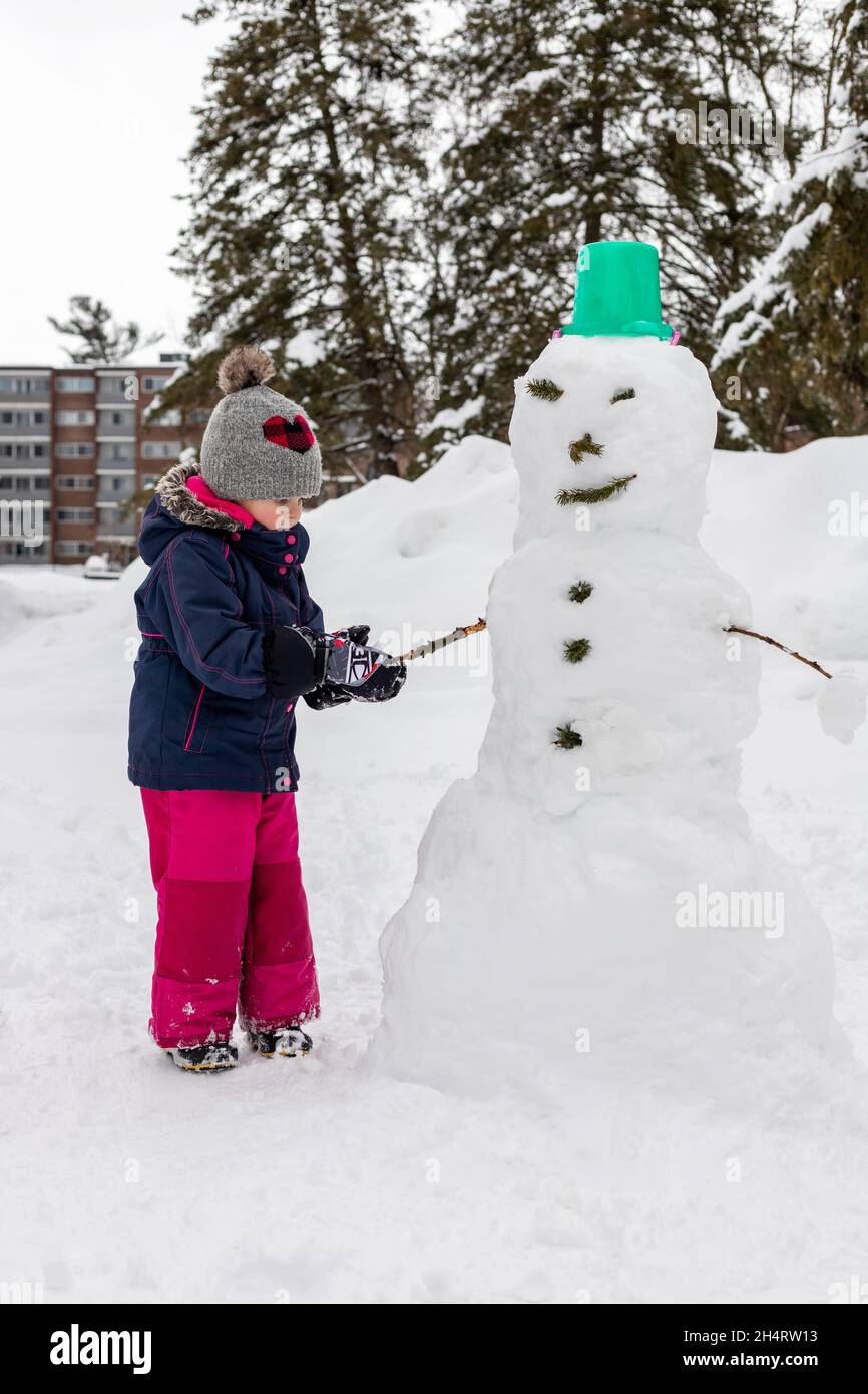 Child making snowman, playing with snow outdoors on snowy cold winter ...