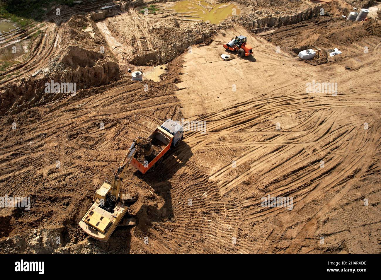 Laying a concrete well ring and sewer pipe at construction site ...