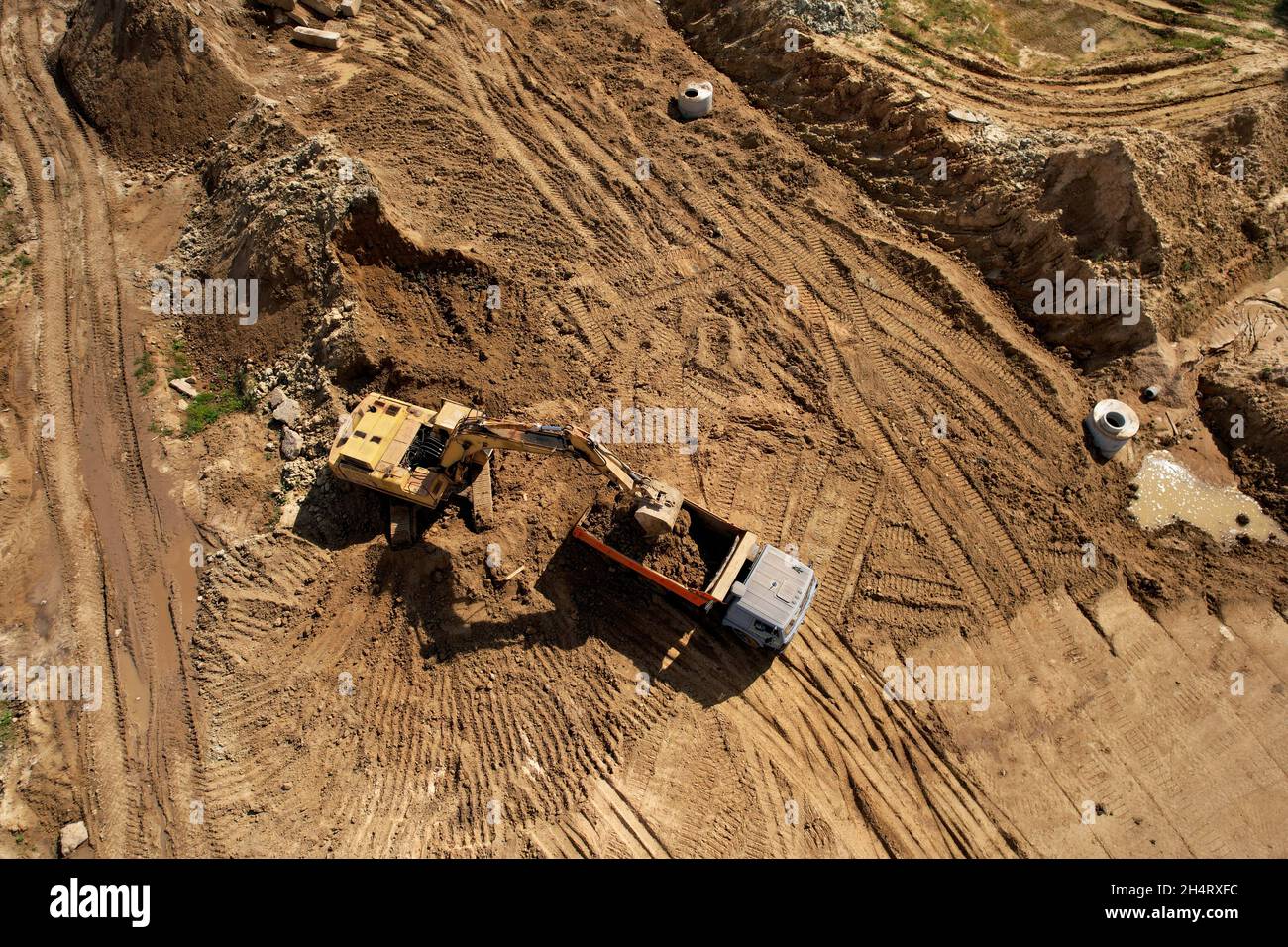 Laying a concrete well ring and sewer pipe at construction site ...