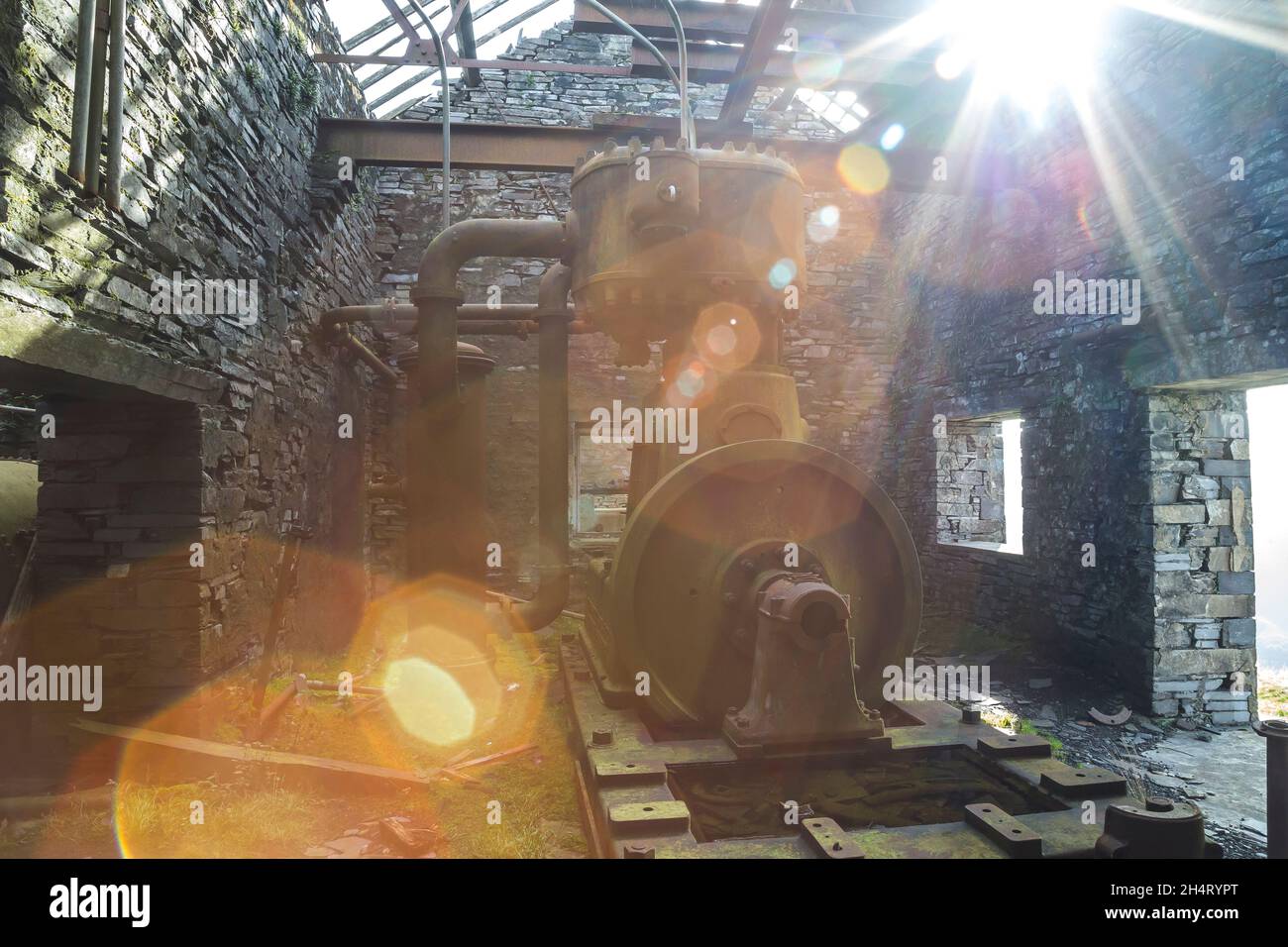 Old machinery in derelict, disused slate quarry building, sun streaming ...