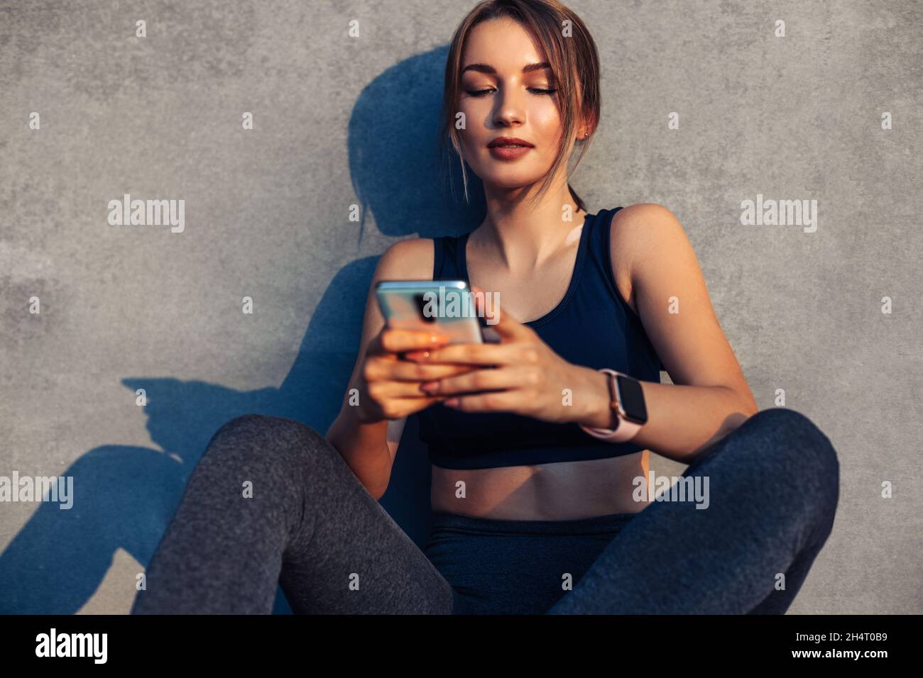 Sports fitness woman using her mobile phone during a break from workout ...