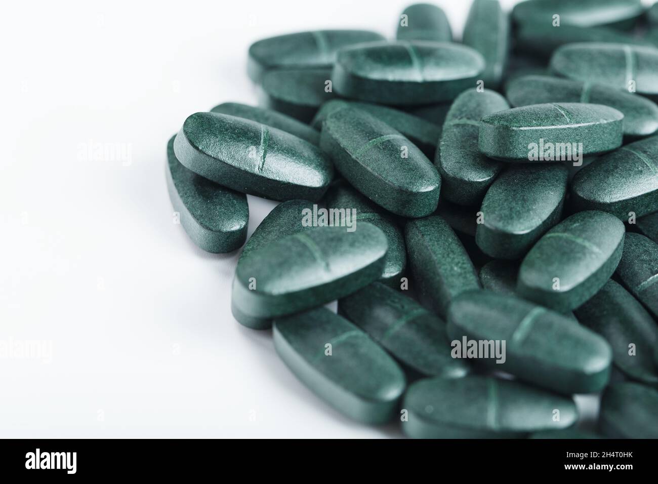 Green tablets with vitamins and spirulina for men on a white background ...