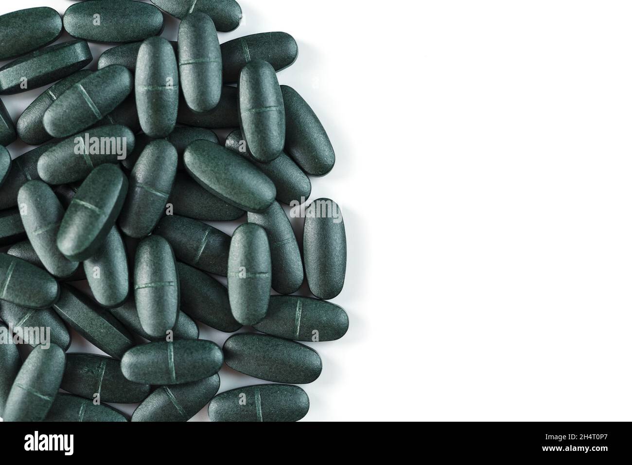 Green tablets with vitamins and spirulina for men on a white background ...