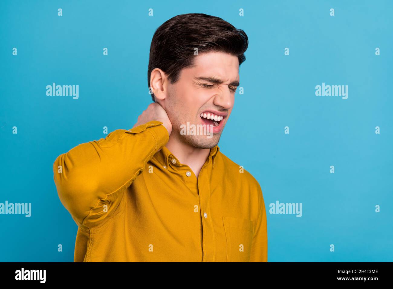 Photo of tired upset young man wear yellow shirt hand arm neck having ...