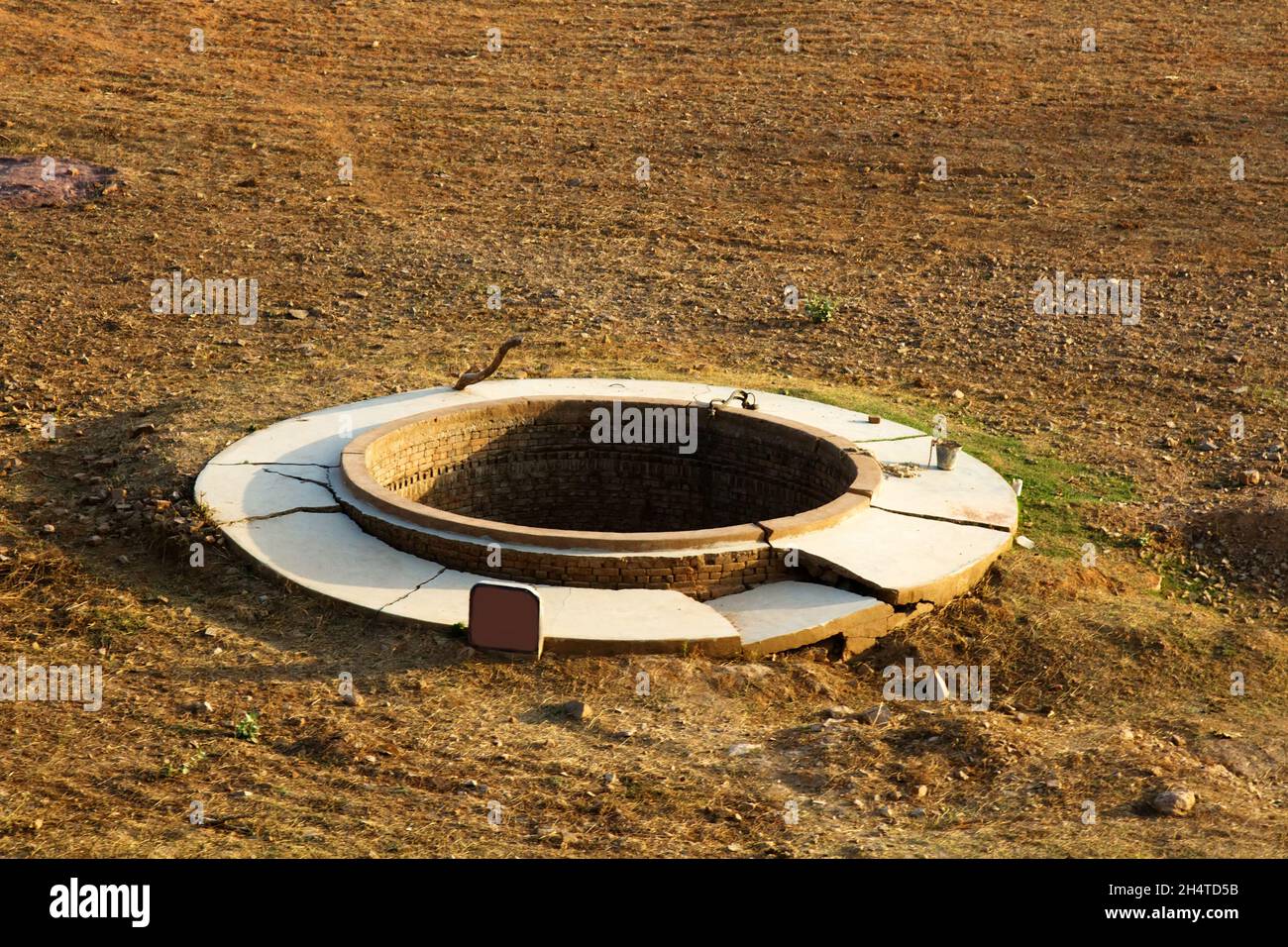 Ancient brick well in a field and a path to it. Farmer's watering hole ...