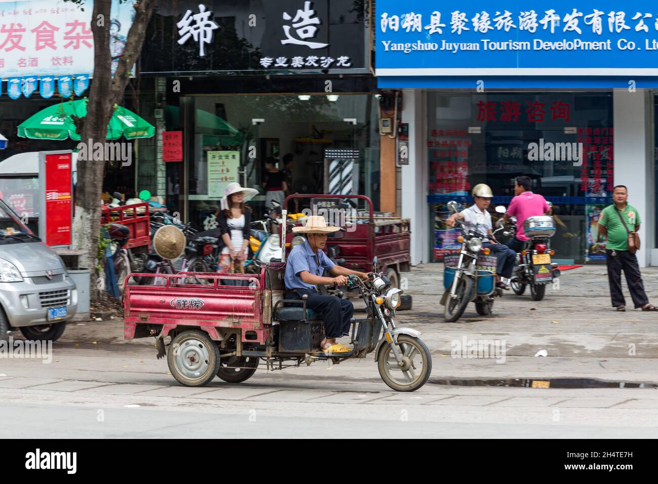 A Chinese man on his three-wheeled utility cart vehcle on the street in ...