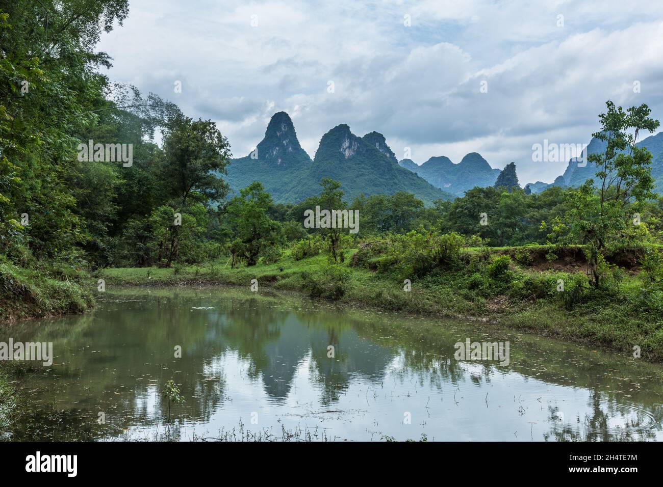 A farmer's pond in rural China with the limestone karst hills of the Li ...