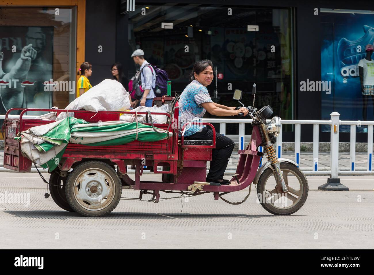 A Chinese woman on her three-wheeled utility cart vehcle on the street ...