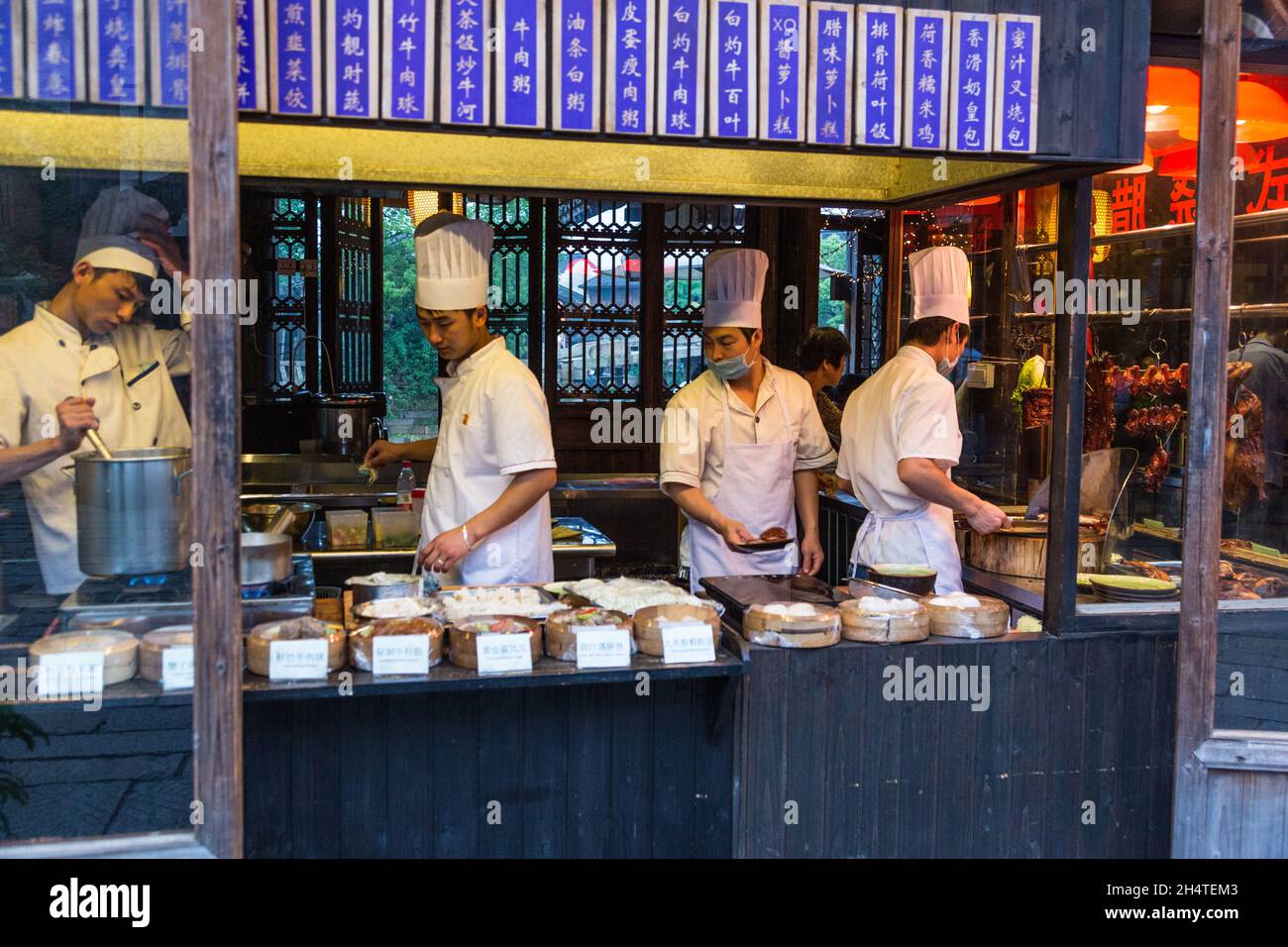 Chinese cooks prepare traditional food in an open restaurant in Wuzhen ...