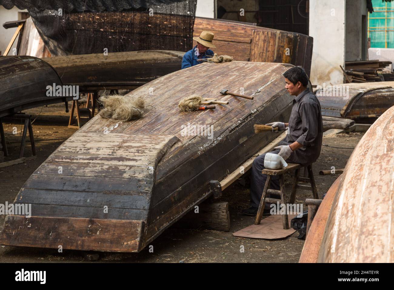 Chinese craftsmen repair a traditional wooden boat in a boatyard in ...