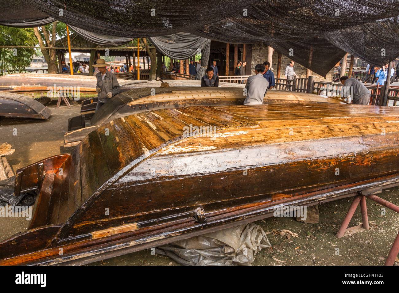 Chinese craftsmen repair a traditional wooden boat in a boatyard in ...