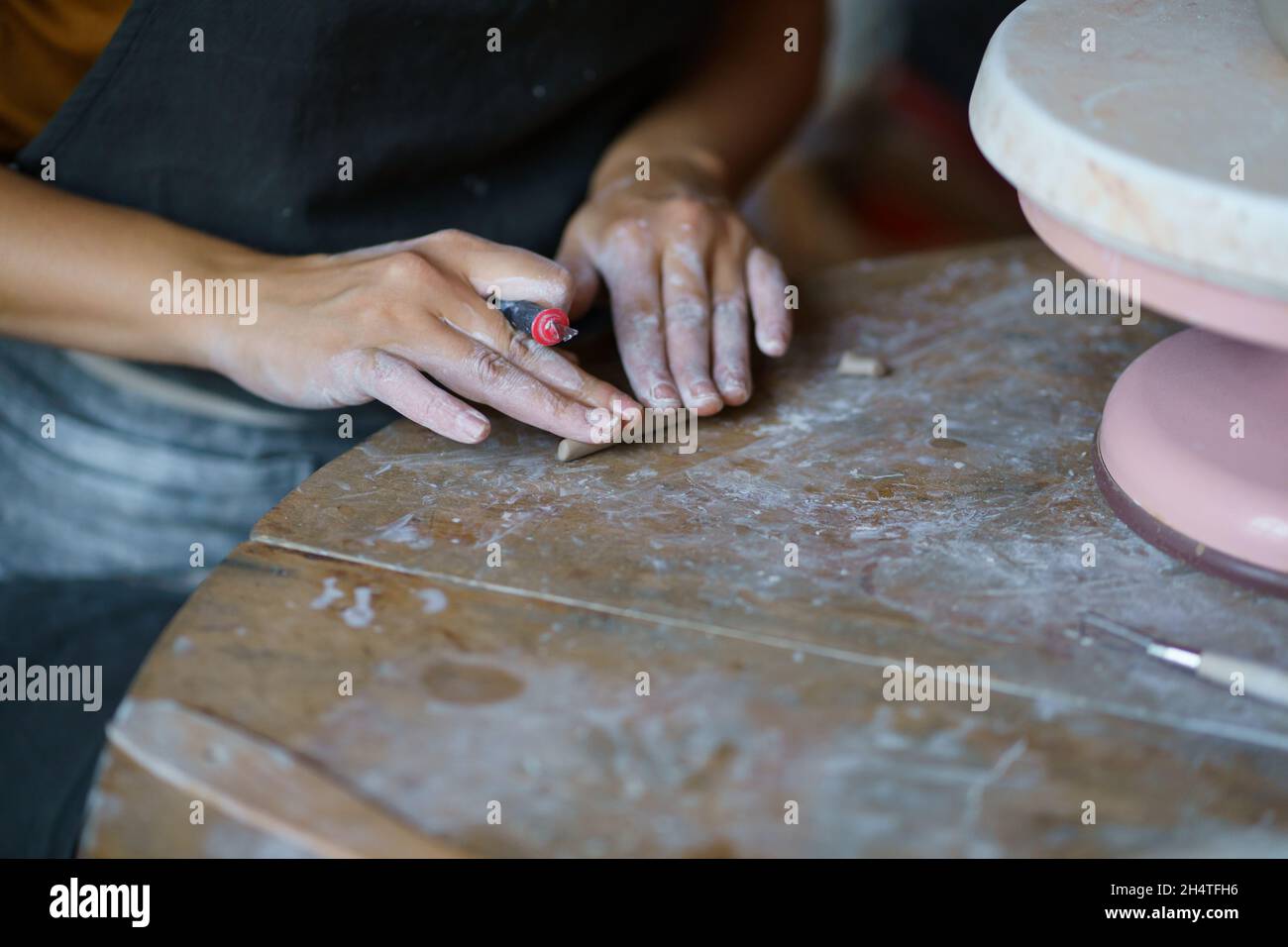 Table in pottery studio with hand of master work on handmade details ...