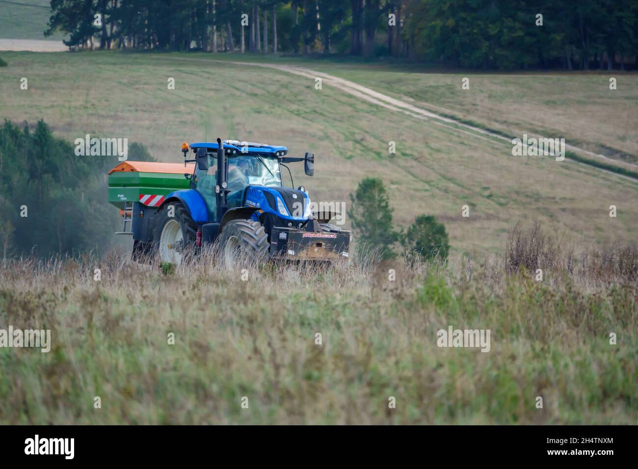 large blue New Holland T7 225 tractor in action with a mounted Amazone ...