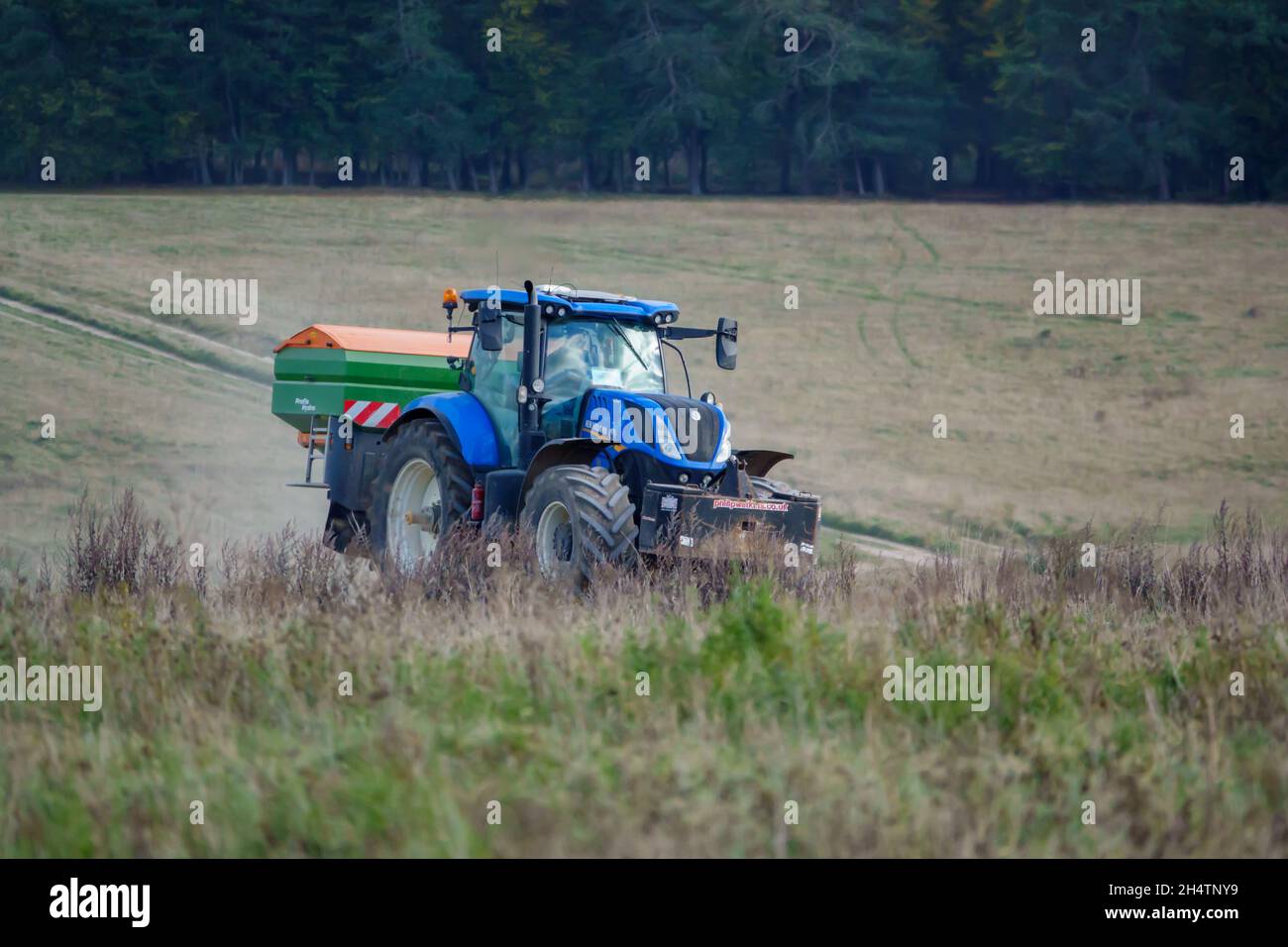 large blue New Holland T7 225 tractor in action with a mounted Amazone ...