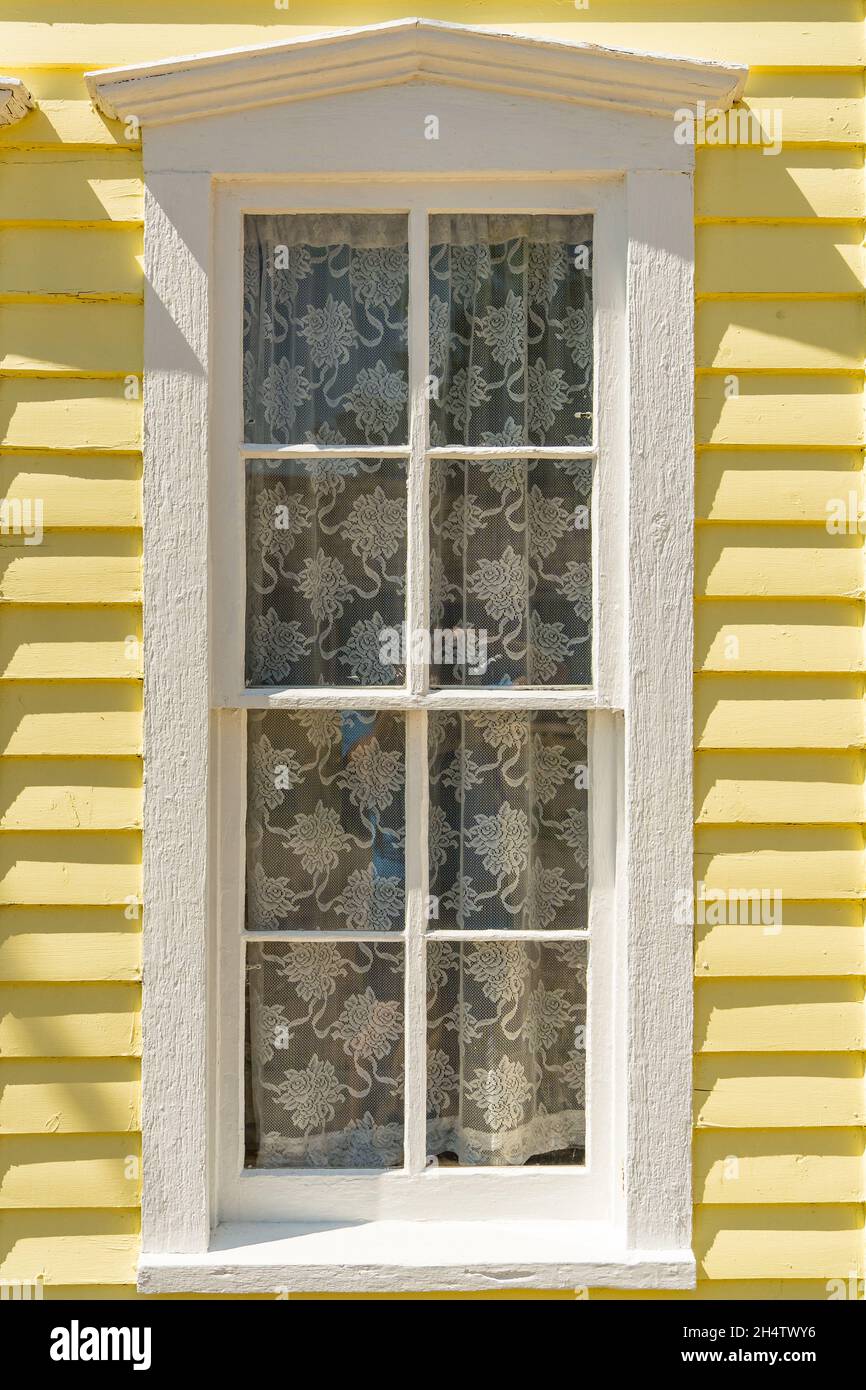 Exterior of old white painted window on bright yellow clapboard house ...