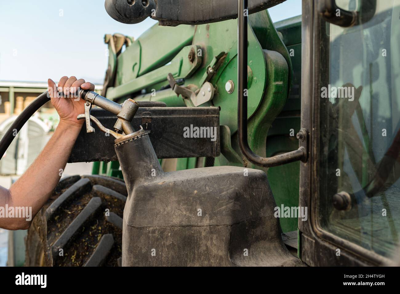 Male farmer filling the fuel of his tractor while working on a farm ...