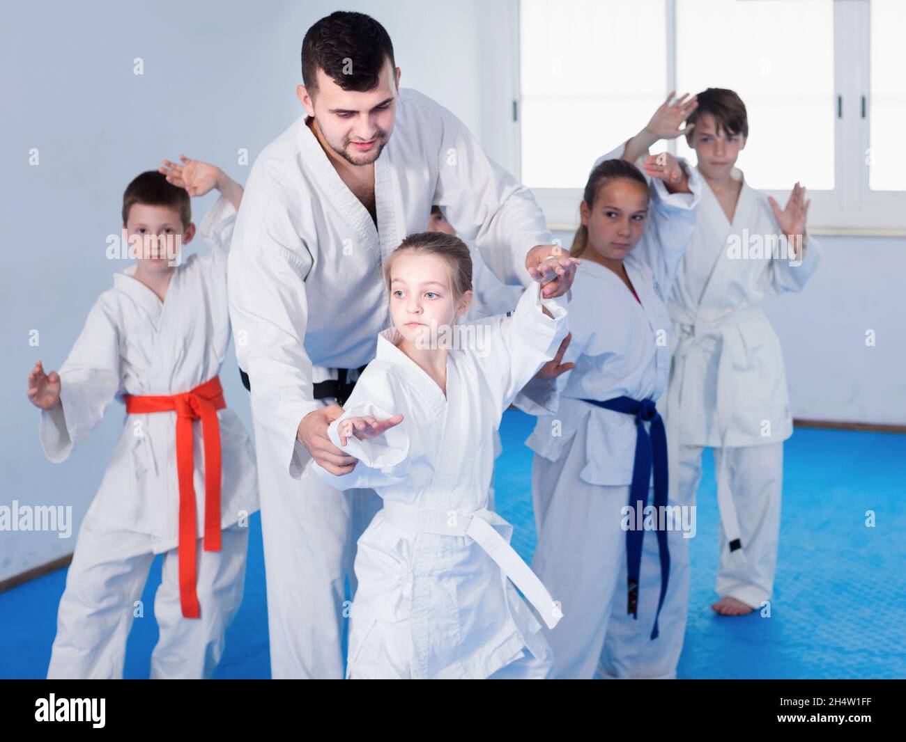 Young children doing karate kicks with male coach Stock Photo - Alamy