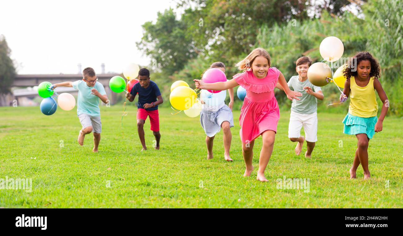 Kids with balloons running through field Stock Photo - Alamy