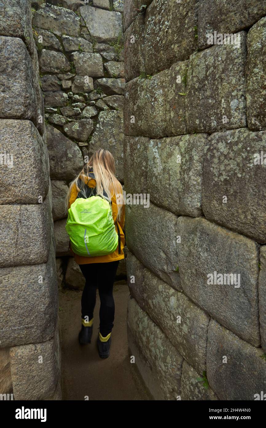 Tourist between narrow stone walls of Machu Picchu, 15th century Inca ...
