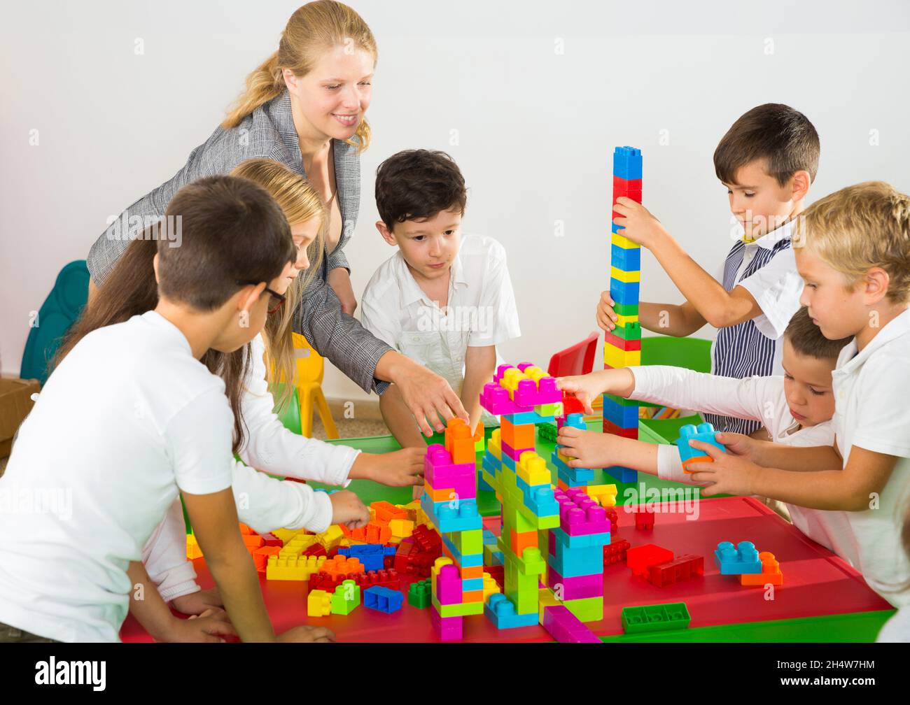 Kids with teacher playing with building blocks Stock Photo - Alamy