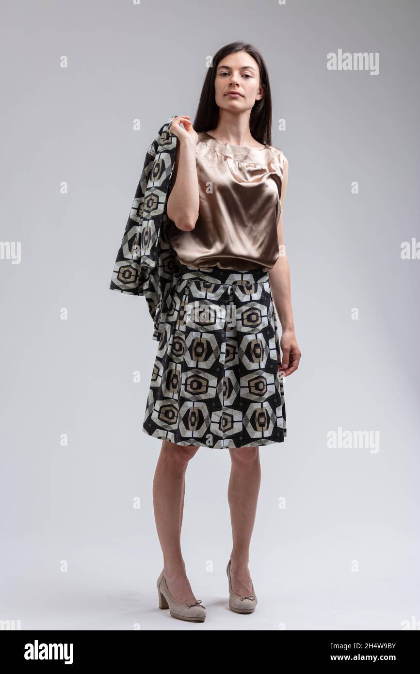 Elegant young woman wearing a stylish skirt and jacket set standing ...