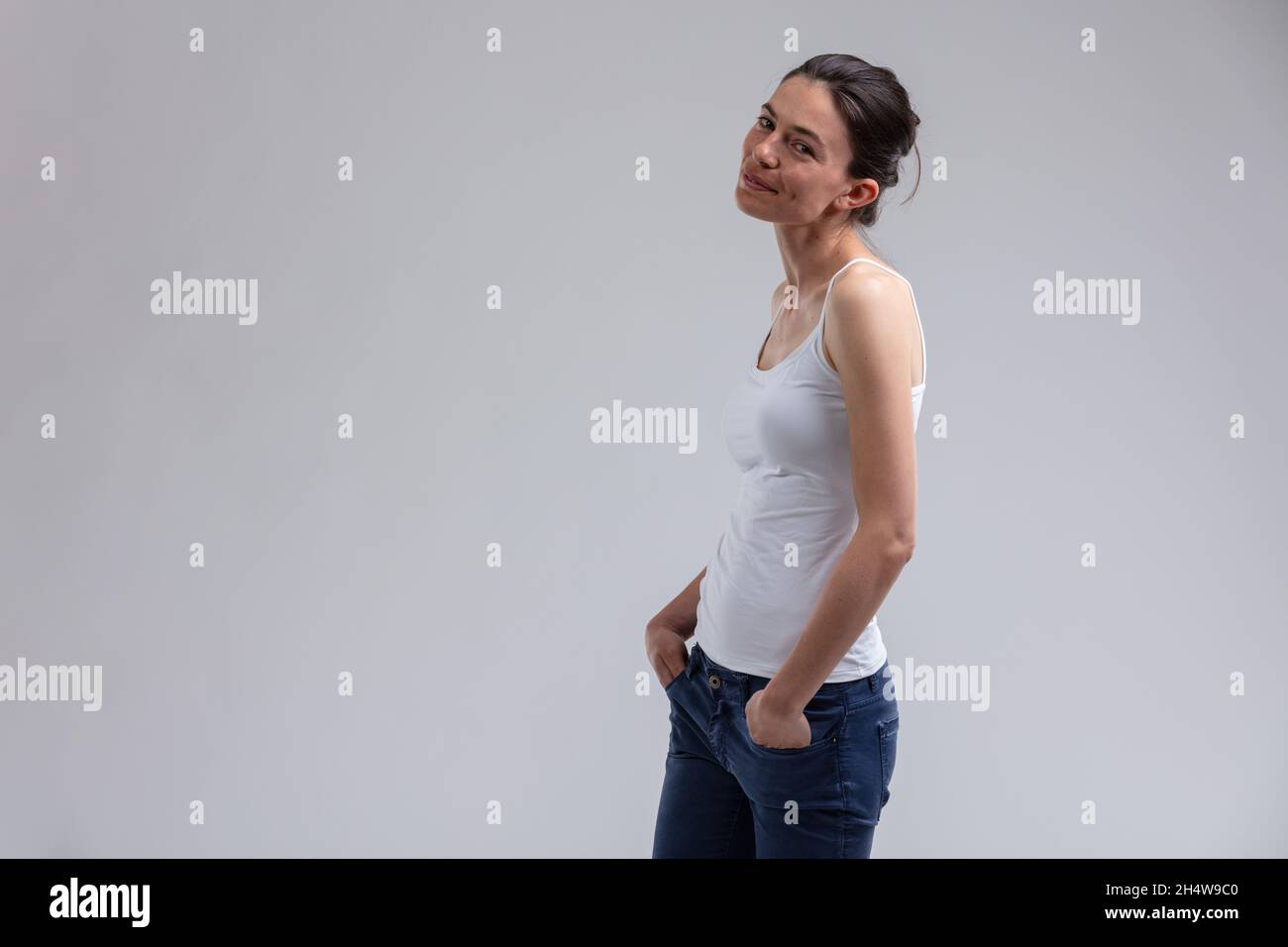 Playful attractive trendy young woman grinning at the camera as she ...