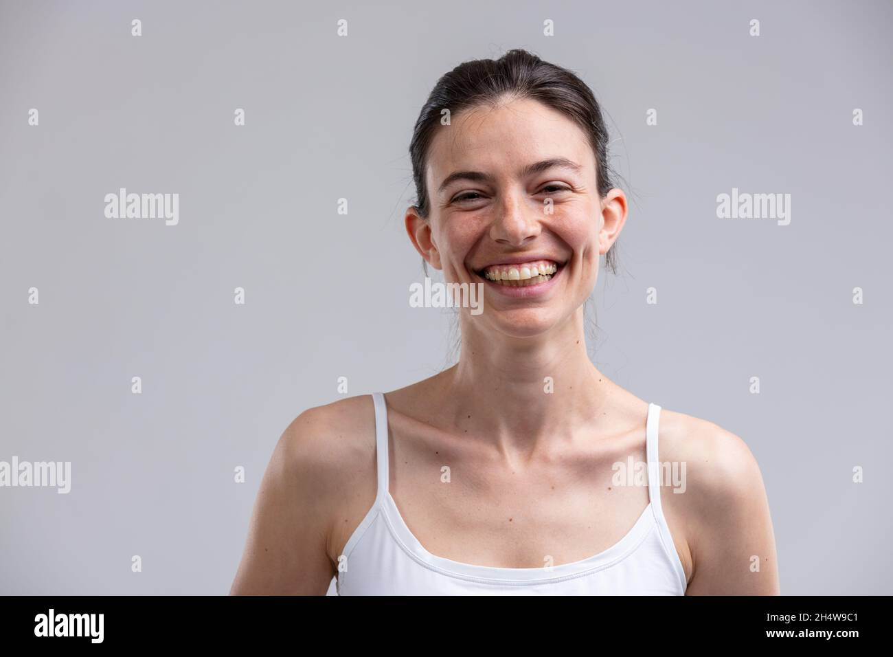 Cute charismatic young woman with a cheeky vivacious grin in a head and ...