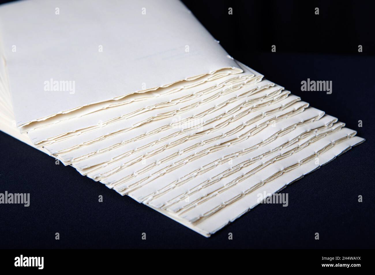 The process of book binding; putting together raw paper folders. Black ...