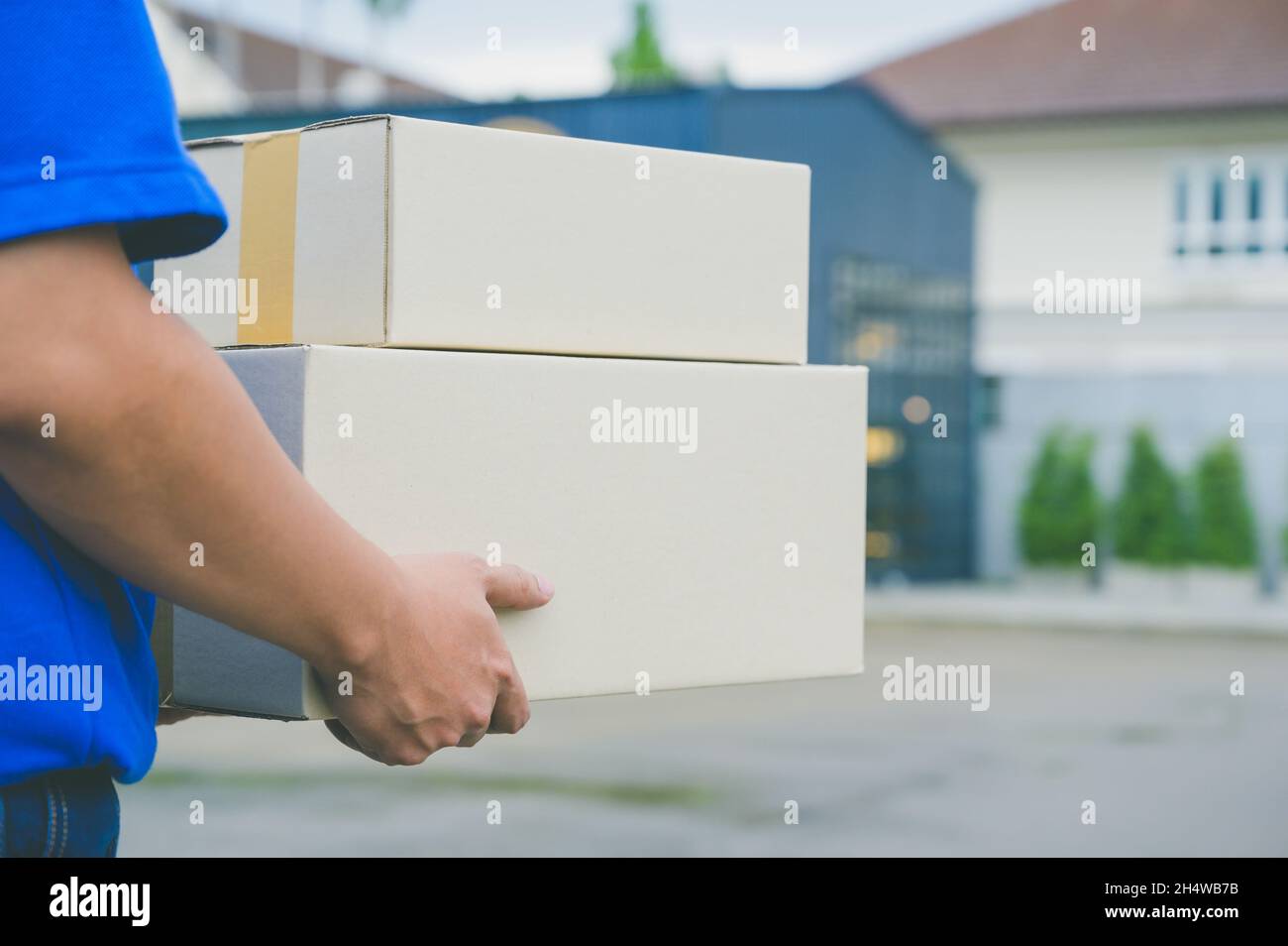 Close up Delivery man in blue uniforms holding parcel cardboard box Stock Photo - Alamy