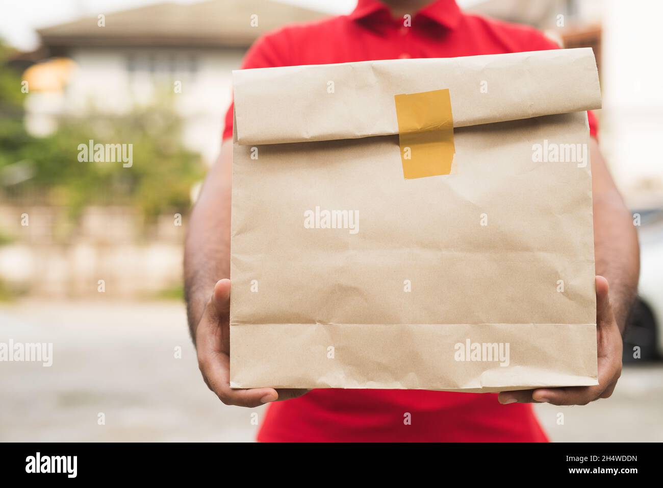 Postman in red uniform holding package Stock Photo - Alamy