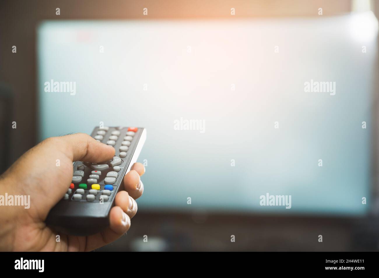 Young man holding television remote control. Hands pointing to tv ...