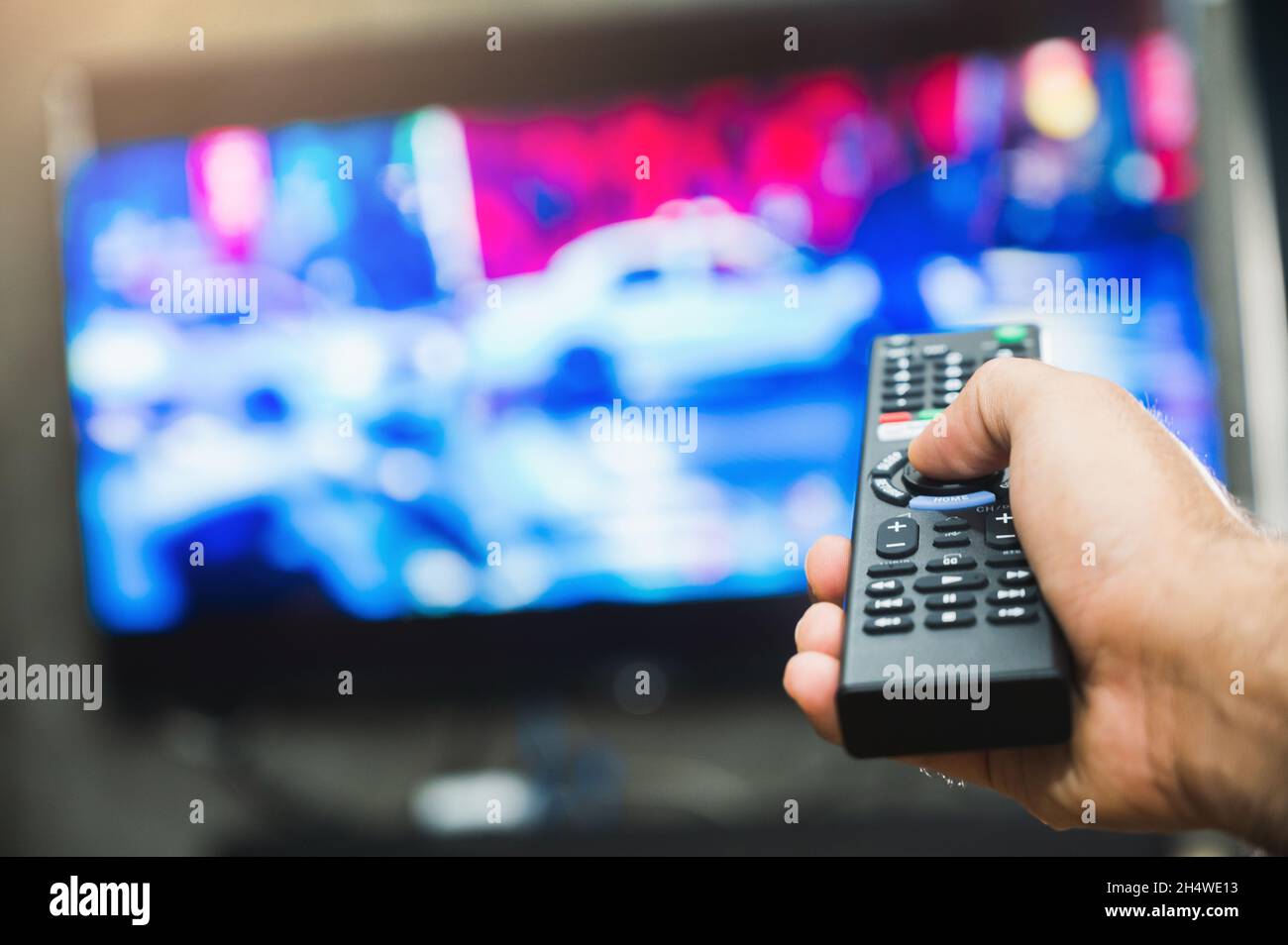 Young man holding television remote control. Hands pointing to tv ...