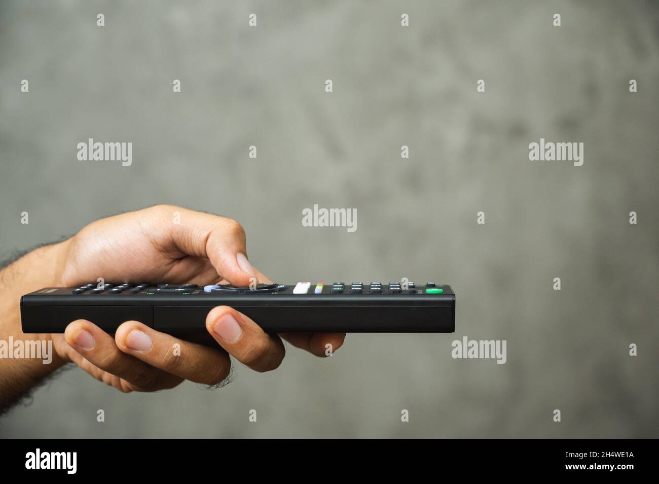 Young man holding television remote control. Hands pointing to tv set ...
