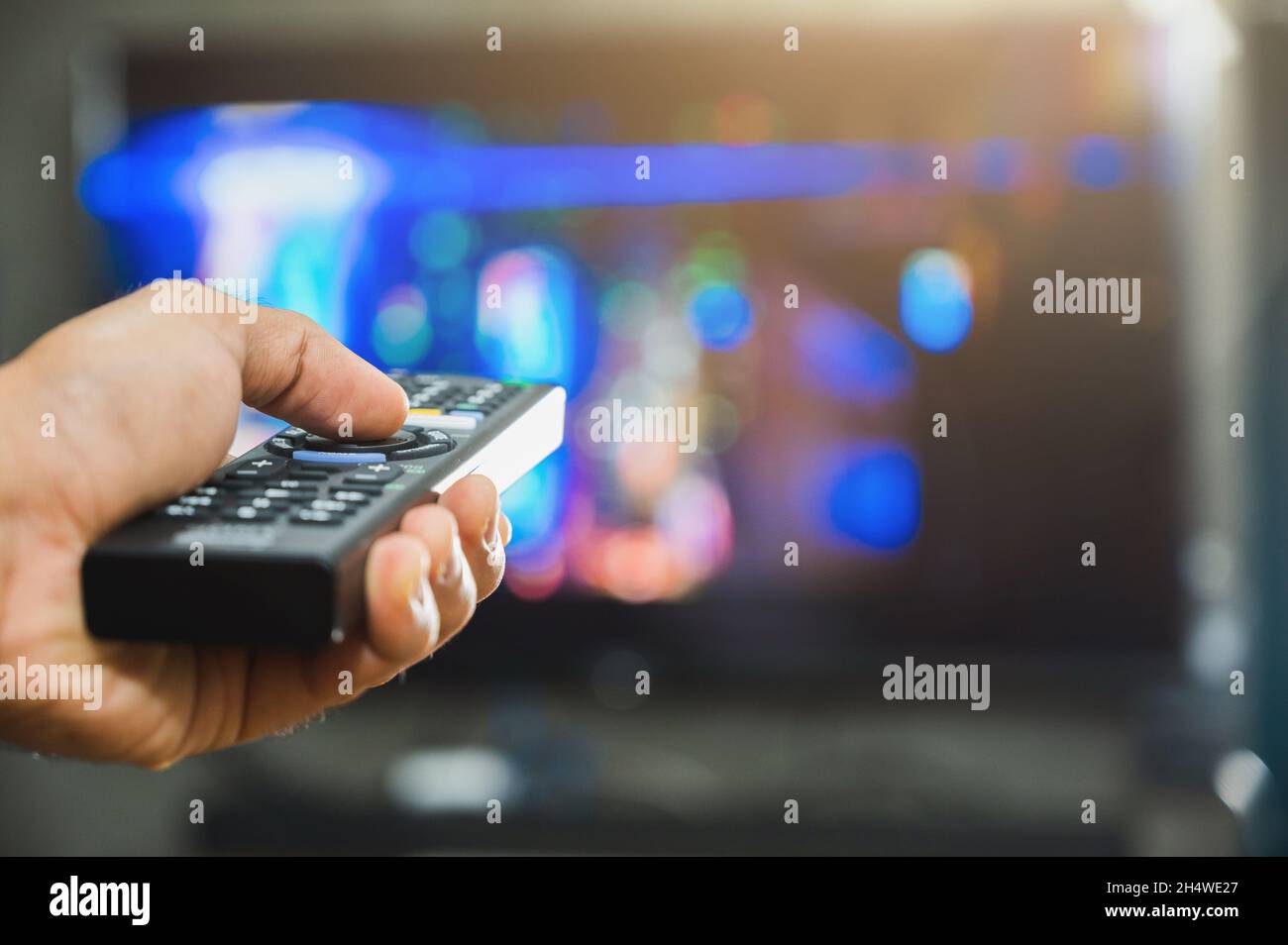 Young man holding television remote control. Hands pointing to tv ...