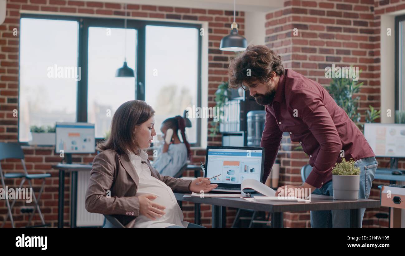 Business woman expecting child and having discussion with man while ...
