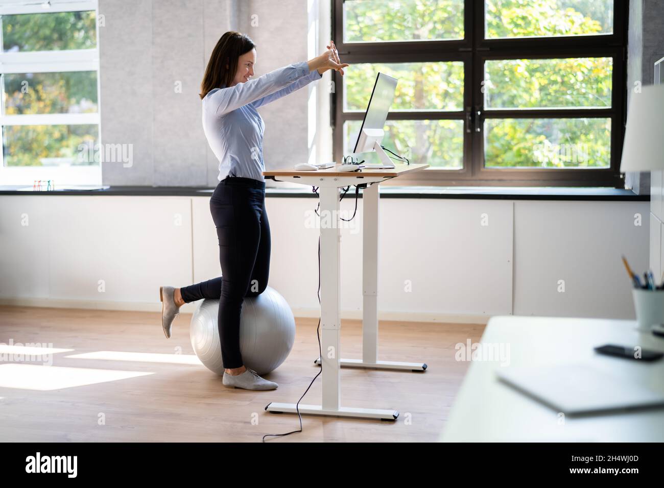 Worker Stretch Exercise At Stand Desk In Office Stock Photo - Alamy