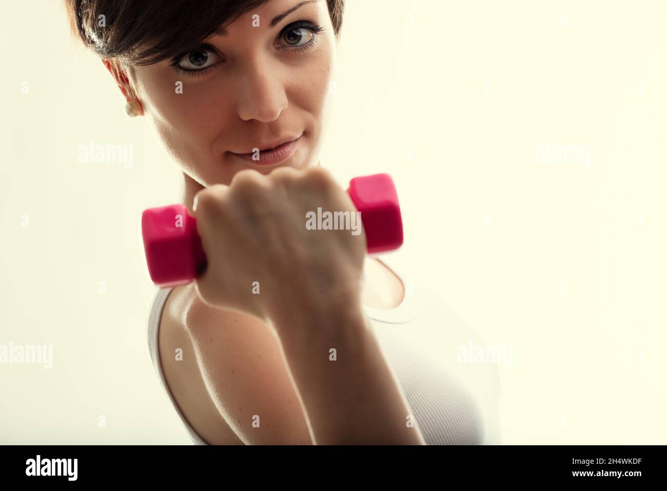 Determined strong fit young woman working out with a dumbbell weight ...