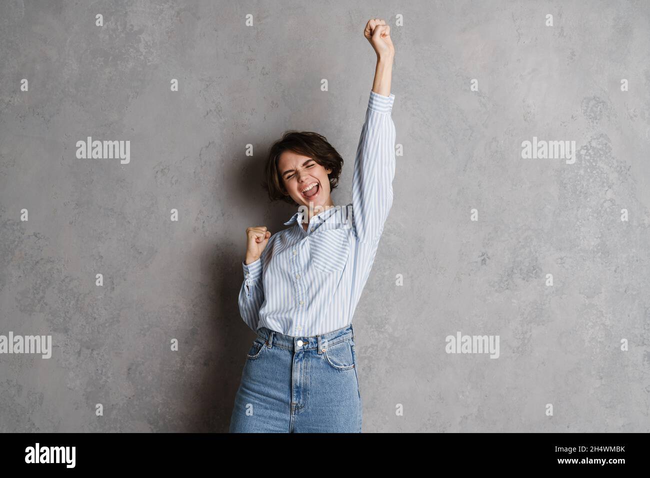 Young brunette woman making winner gesture and screaming isolated over ...