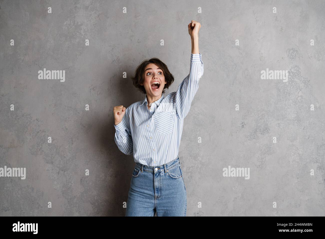 Young brunette woman making winner gesture and screaming isolated over ...