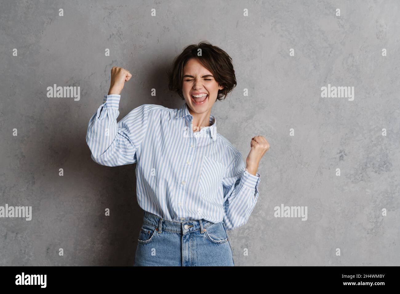 Young brunette woman making winner gesture and screaming isolated over ...