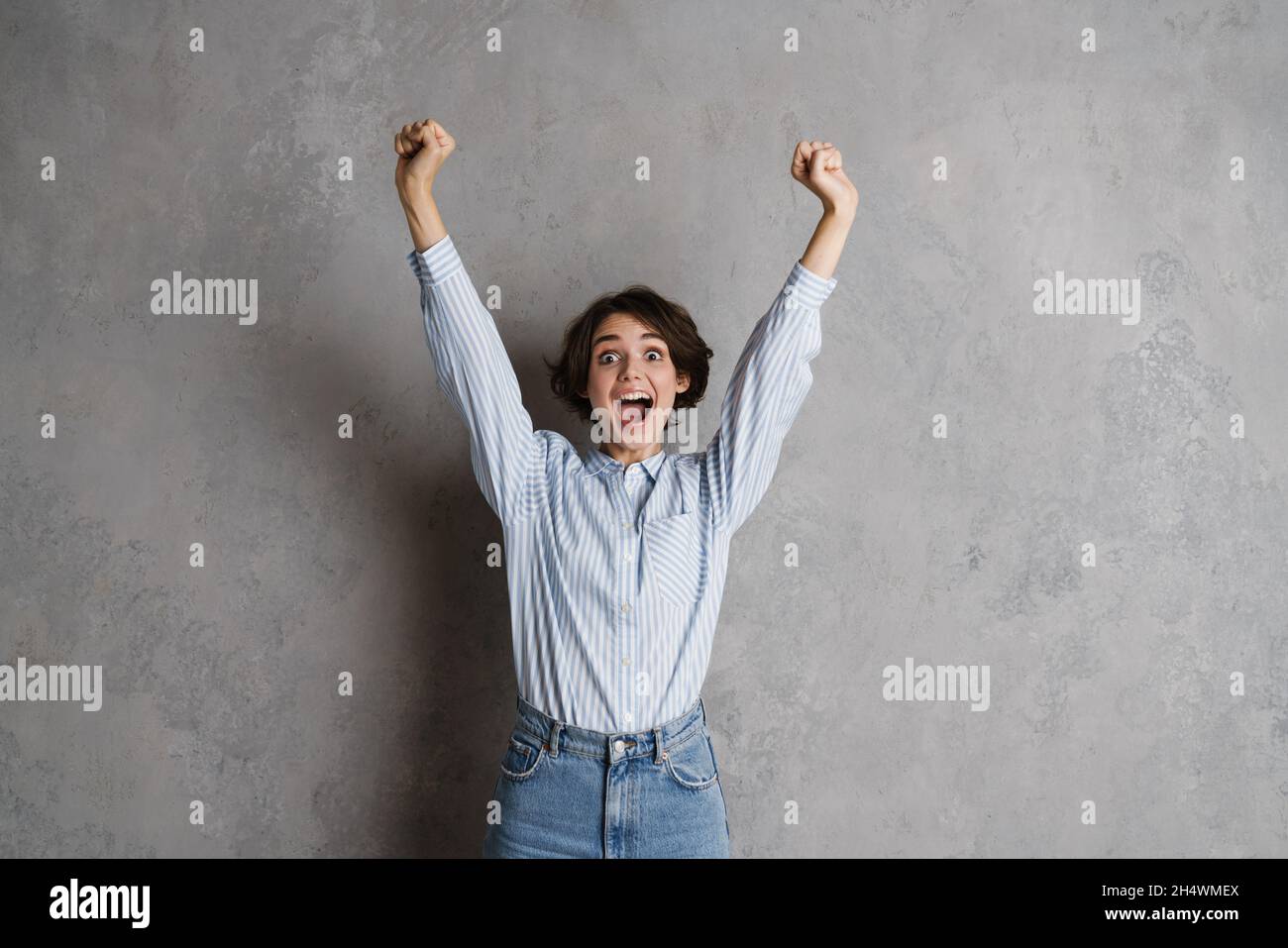 Young brunette woman making winner gesture and screaming isolated over ...