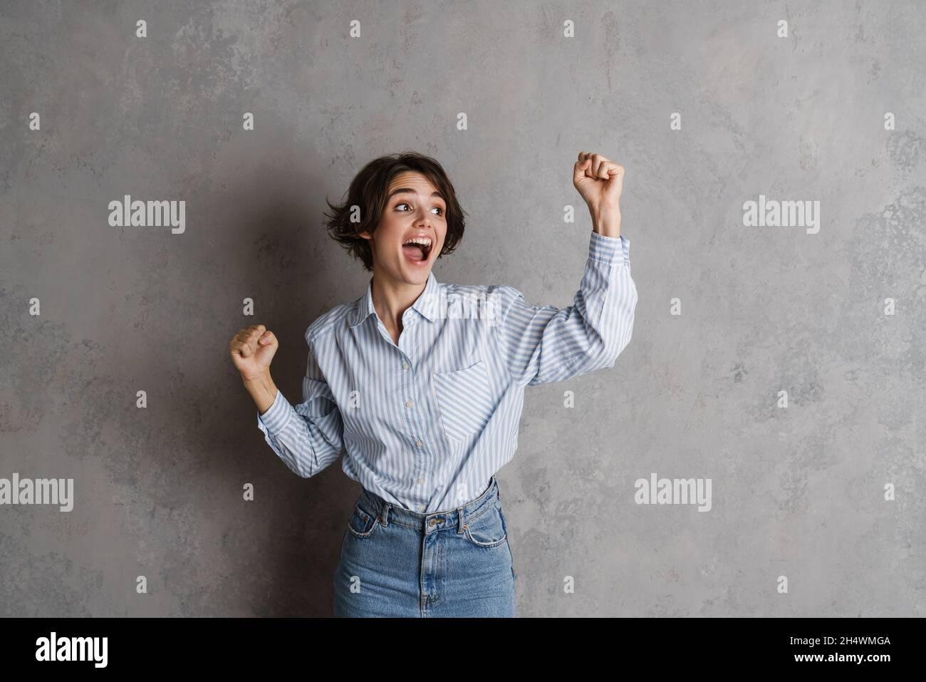 Young brunette woman making winner gesture and screaming isolated over ...